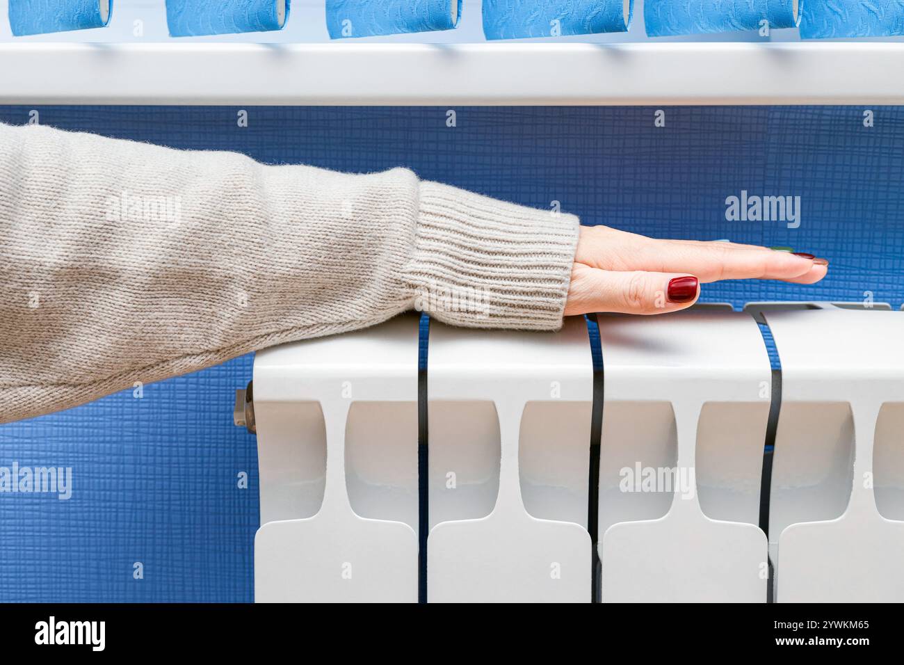 A woman checks the temperature of a heating radiator with her hand ...