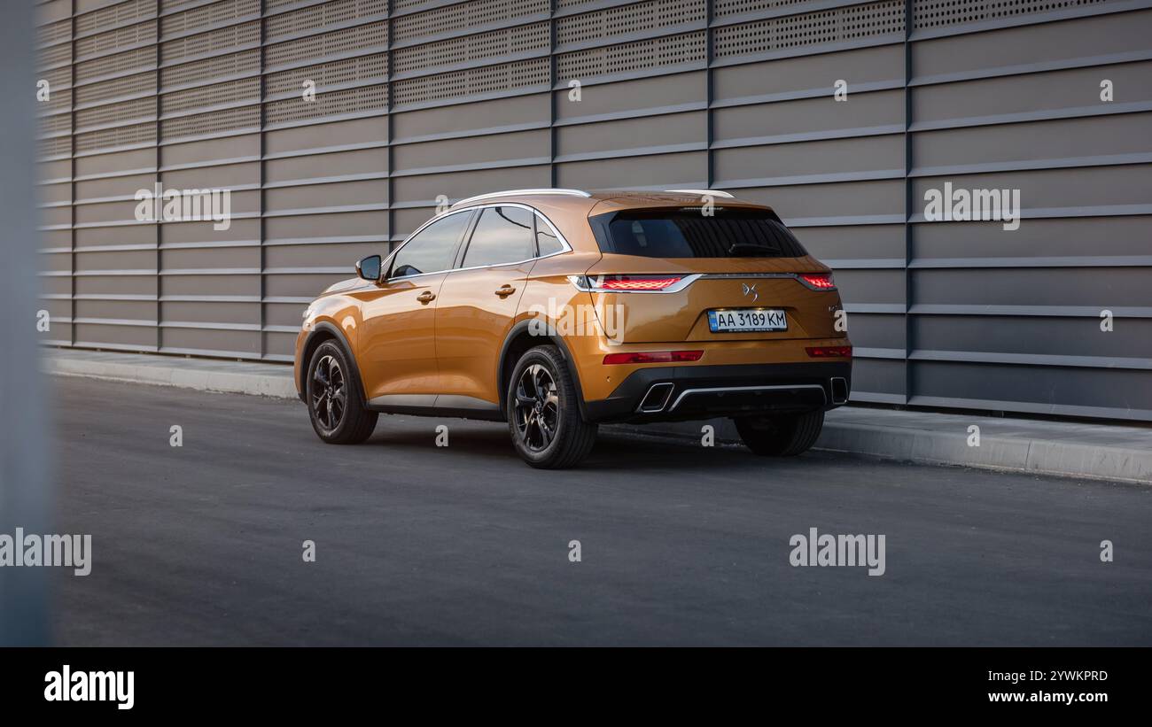 Light brown DS7 parked near dark grey wall with horizontal bars. Rear ...