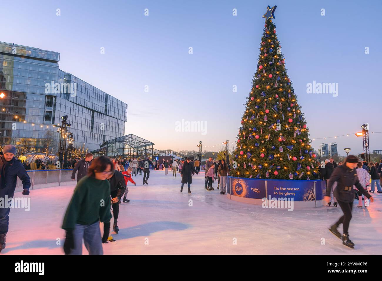 People ice skating around a tall Christmas tree on a ice rink at ...