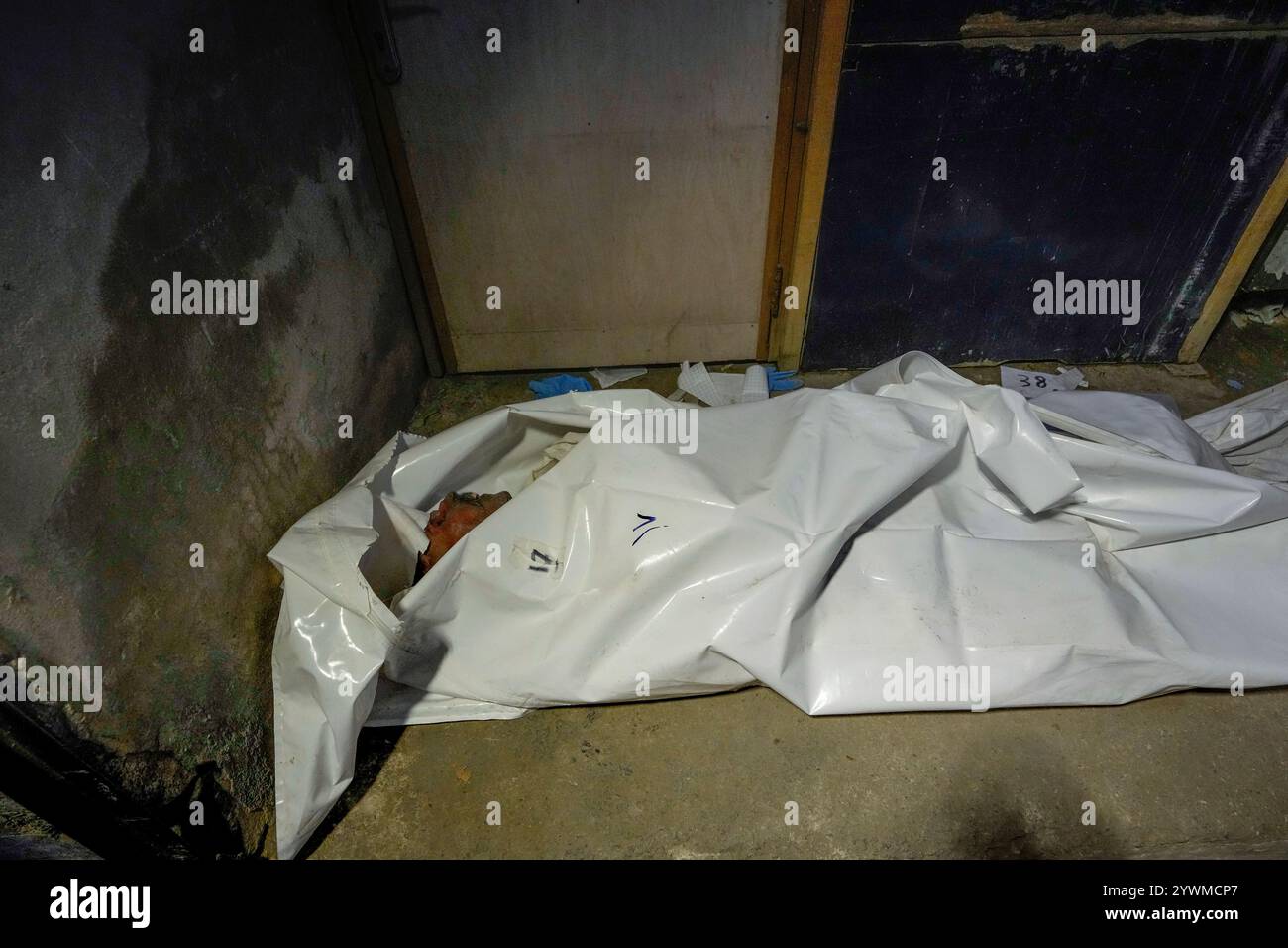 EDS NOTE: GRAPHIC CONTENT - A body wrapped in a plastic bag lies on the ...