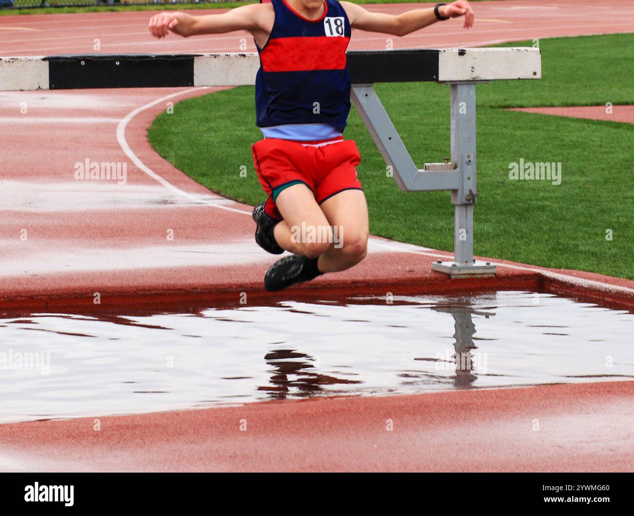 A young athlete in red and blue gear does a cannonball into water ...