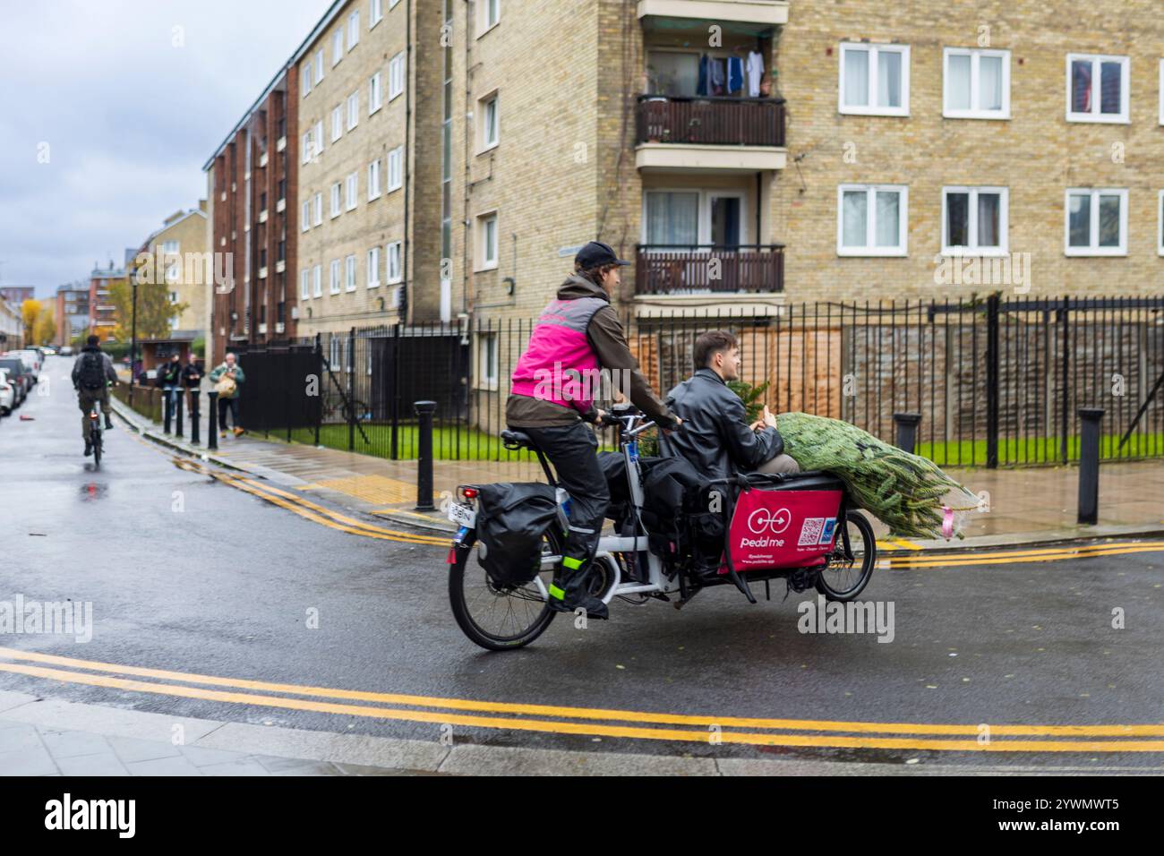 London, UK - December 2, 2024: A young man riding a rickshaw transports ...