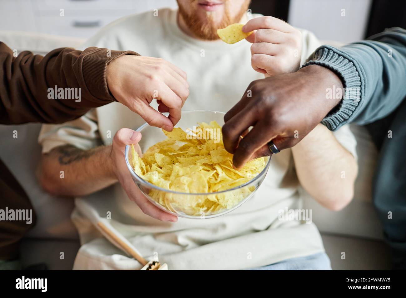 Front view closeup of diverse male hands grabbing potato chips from ...