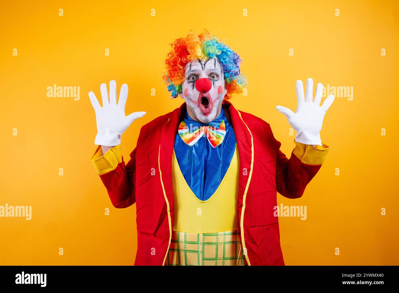 Shocked clown with rainbow wig, wide-eyed, hands up Stock Photo - Alamy