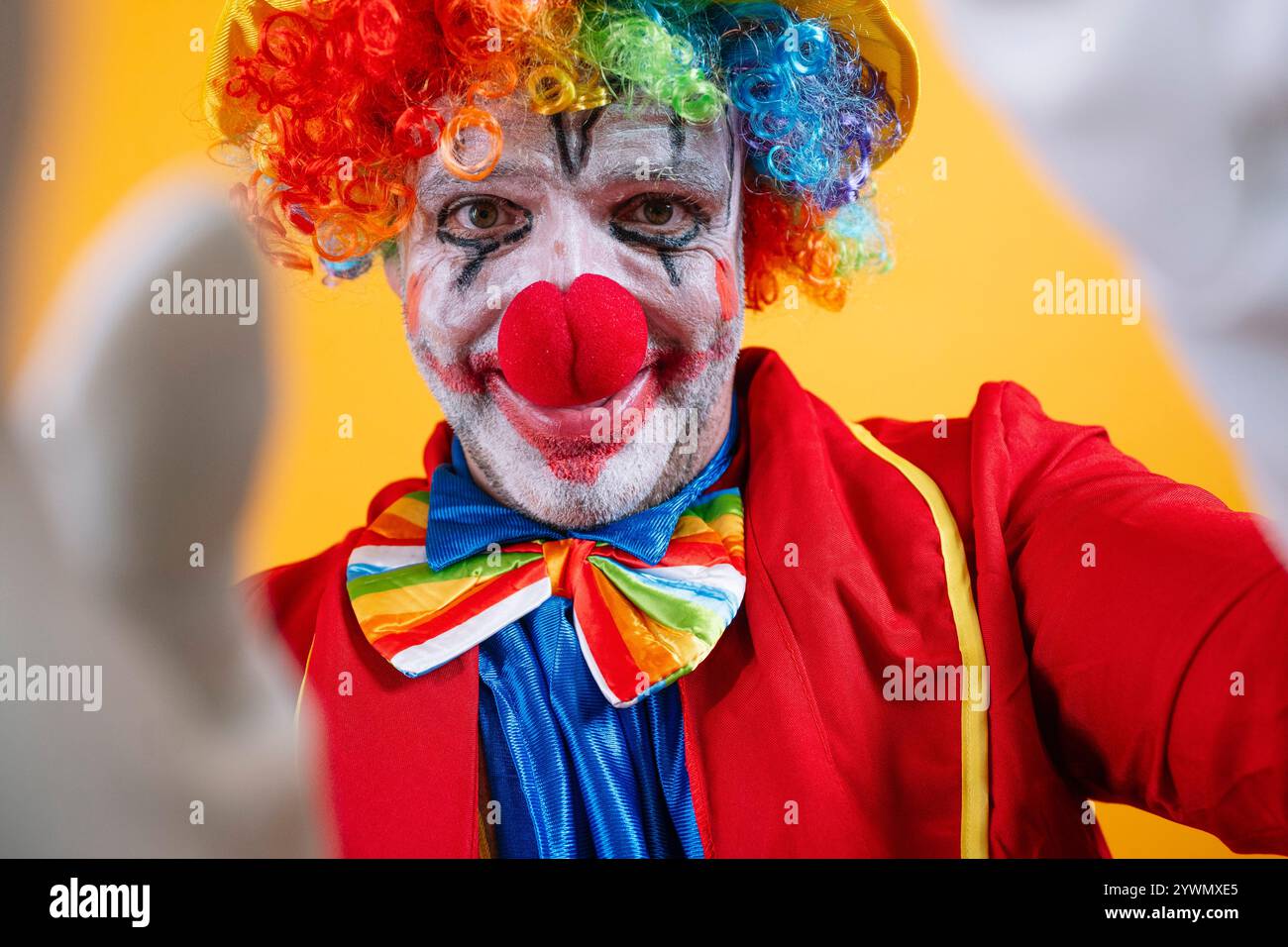 Happy clown in colorful costume against vibrant yellow background Stock ...