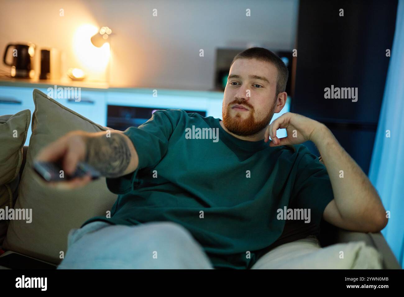 Front view portrait of relaxed bearded young man lounging on couch and ...