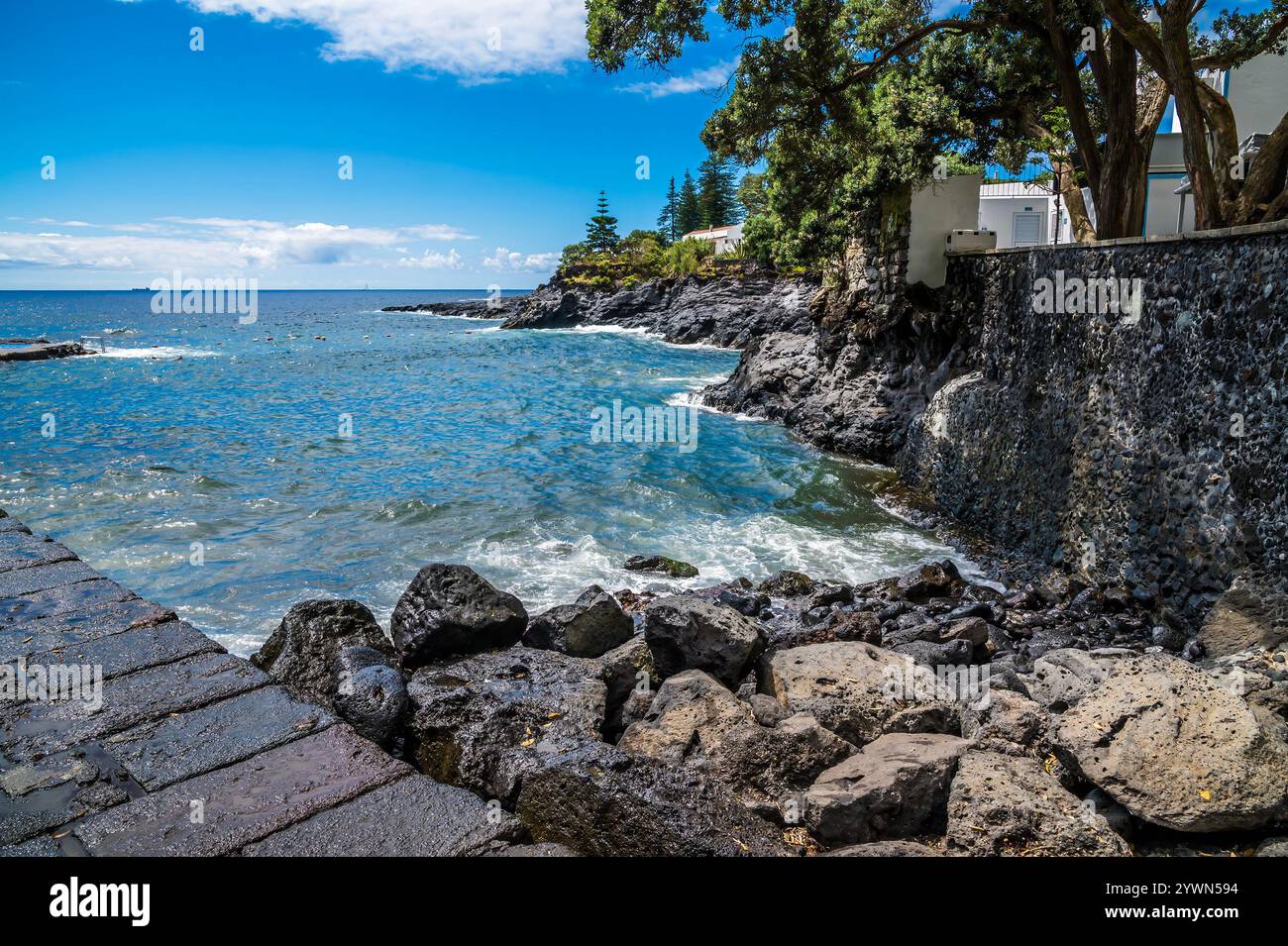 A view along the volcanic black sand beach at Caloura on the island of ...