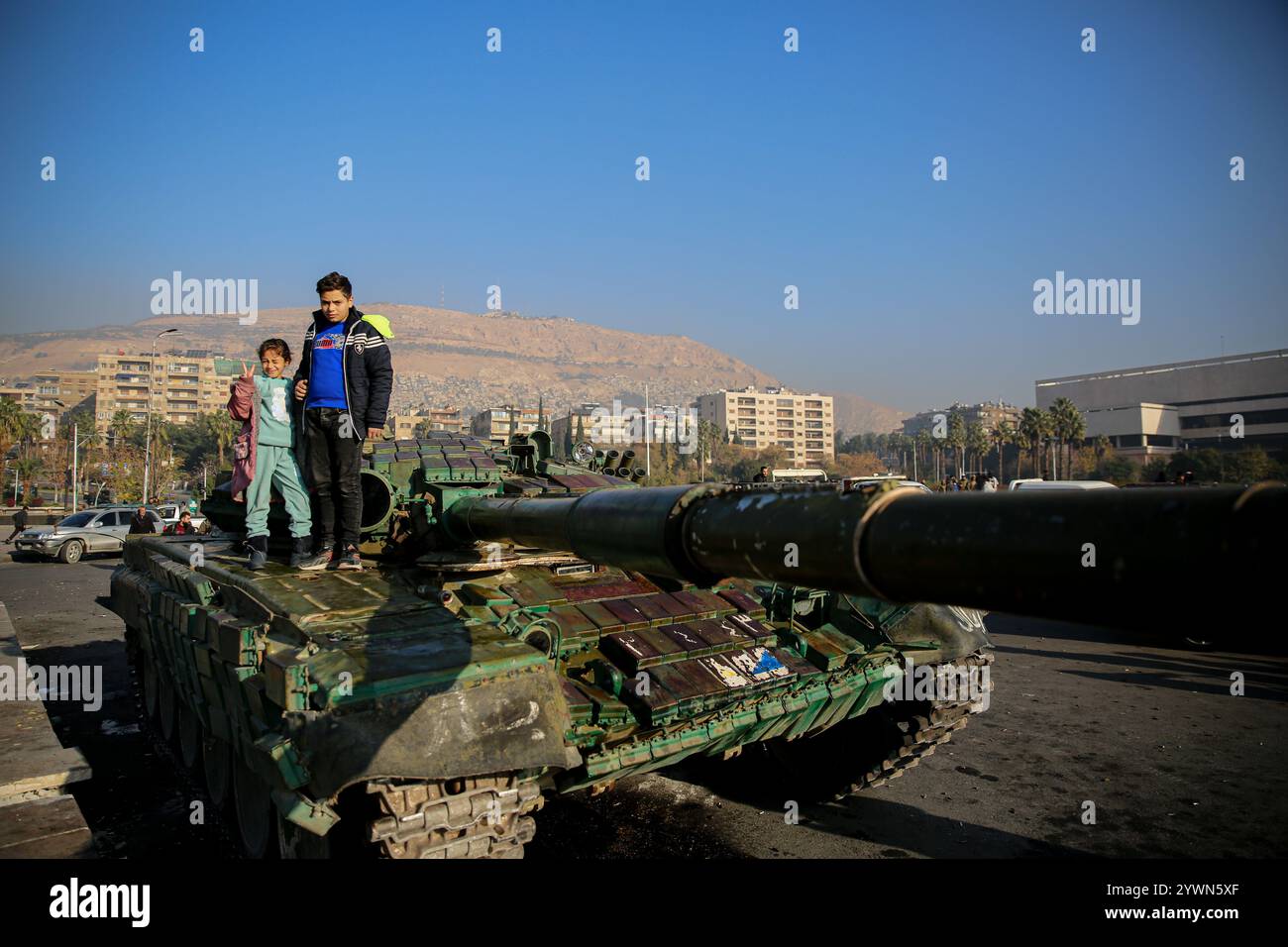 Damascus, Syria. 09 December 2024. A child poses on an abandoned tank ...