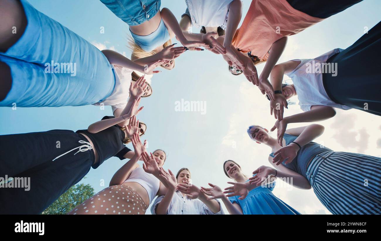 Group of young friends are standing in a circle with their hands ...