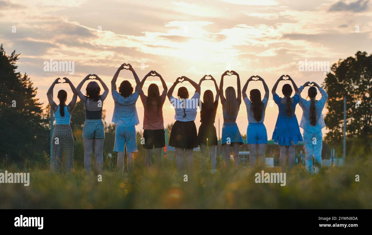 Young graduates waving farewell in a field at sunset, marking the end ...