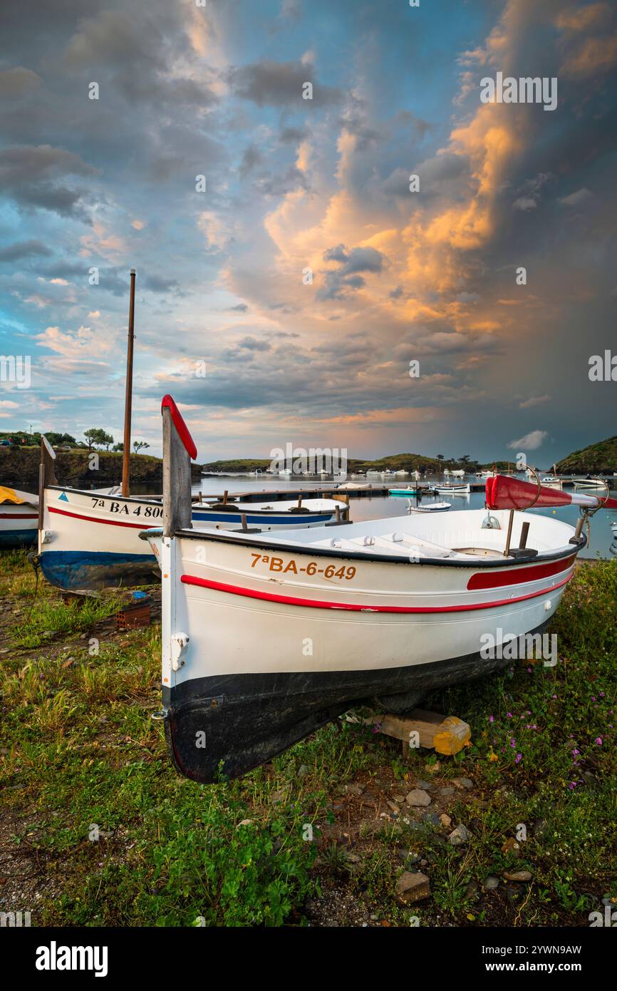 Sailboats on the shore of Portlligat Bay under a dramatic evening sky ...