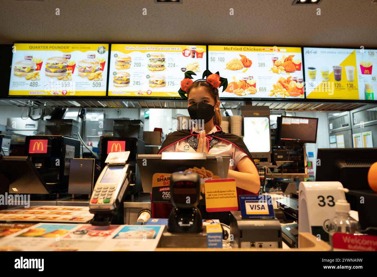 CHIANG MAI, THAILAND - OCTOBER 26, 2023: a female cashier in uniform performing wai at McDonald ...
