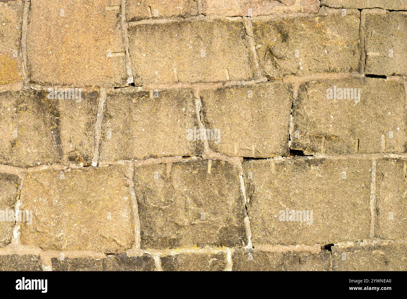Textured stone wall displays various weathering patterns formed over ...
