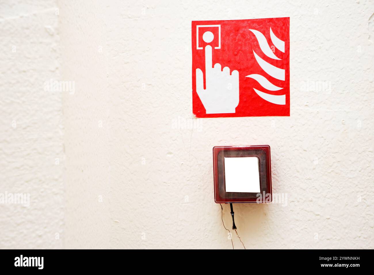 Fire alarm button encased in glass over a sign showing a finger pushing ...