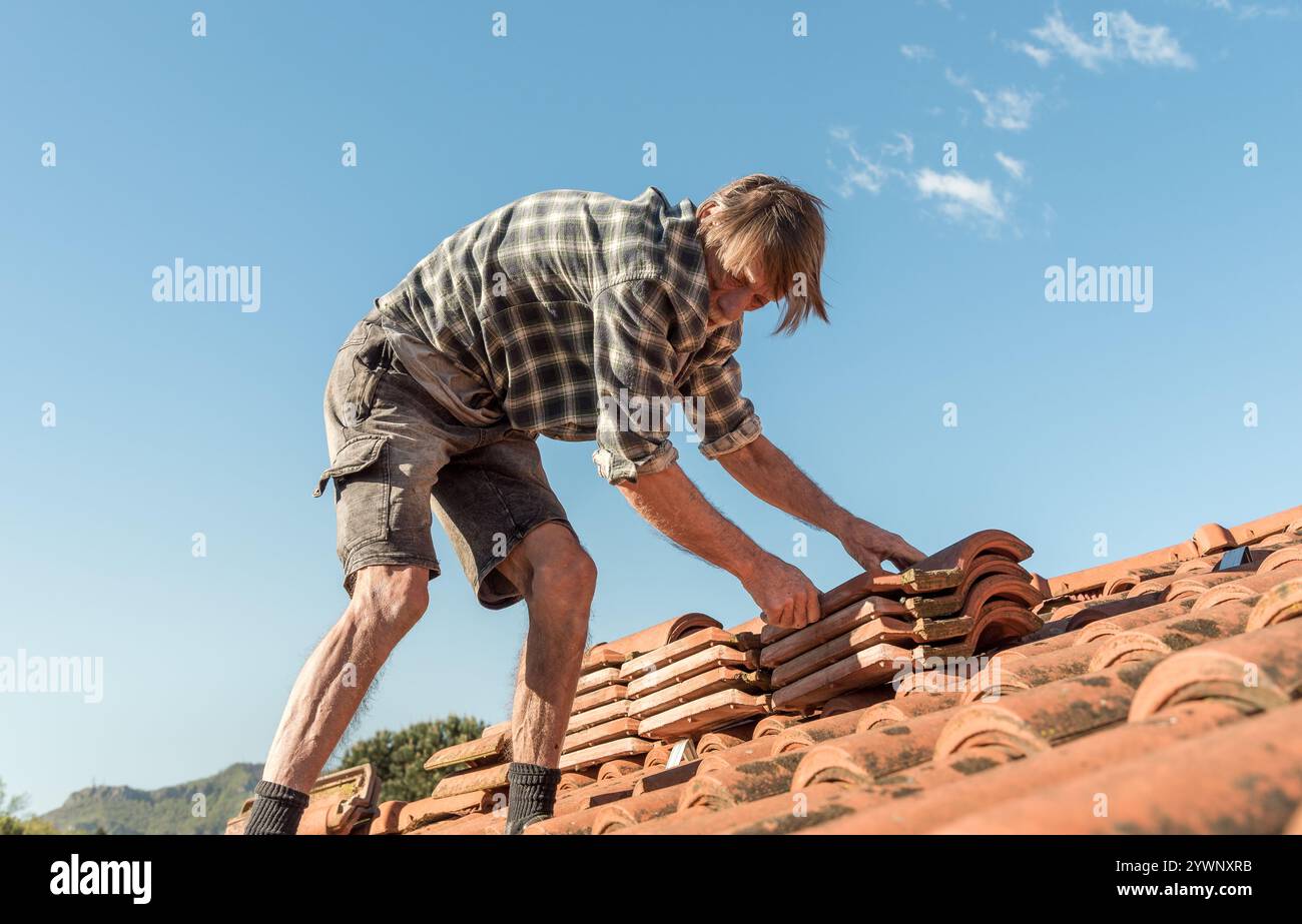 A roofer inspecting and repairing a roof on a sunny day. Maintenance work of the house Stock ...