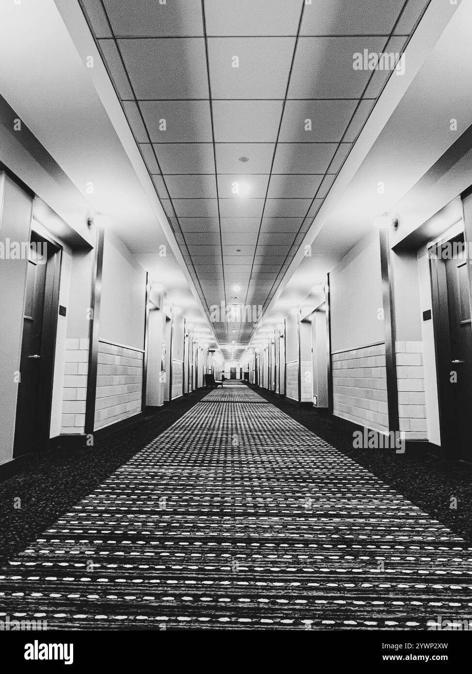 The black-and-white image captures a long, narrow hallway stretching ...