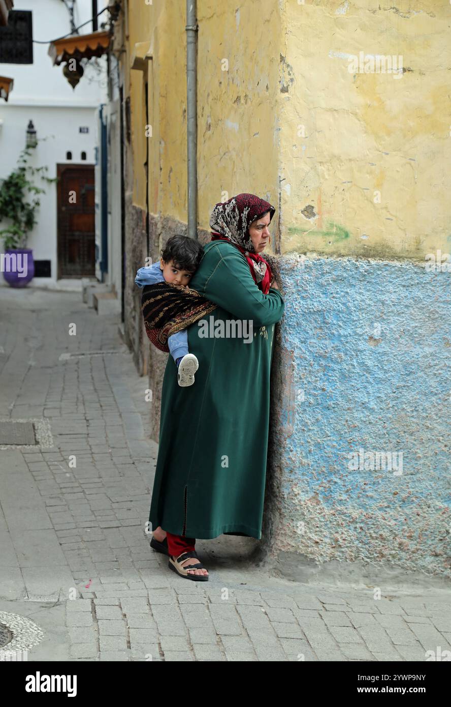 Moroccan woman carrying a child in the kasbah of Tangiers Stock Photo ...