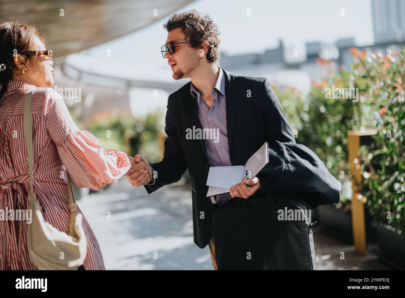 Multicultural business partners engaged in an outdoor meeting handshake ...