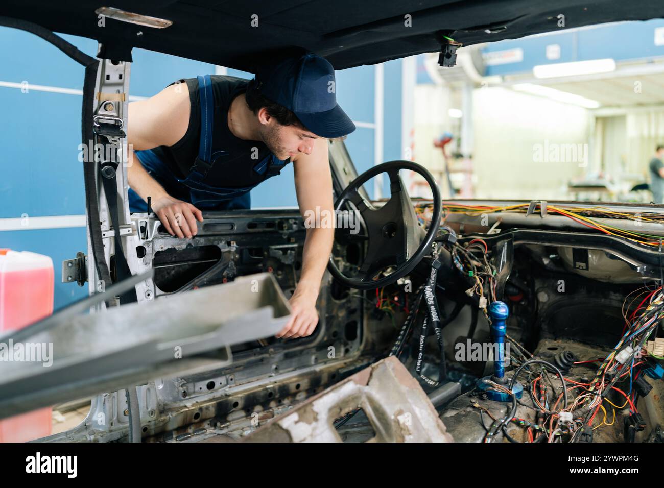 View from interior of old vehicle to mechanic in blue overalls ...
