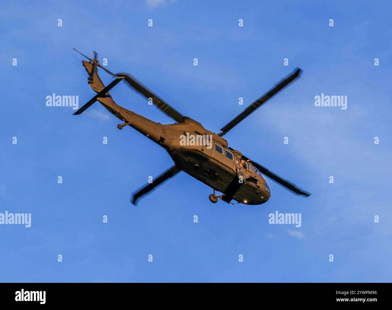 A military helicopter maneuvers gracefully through bright blue skies ...