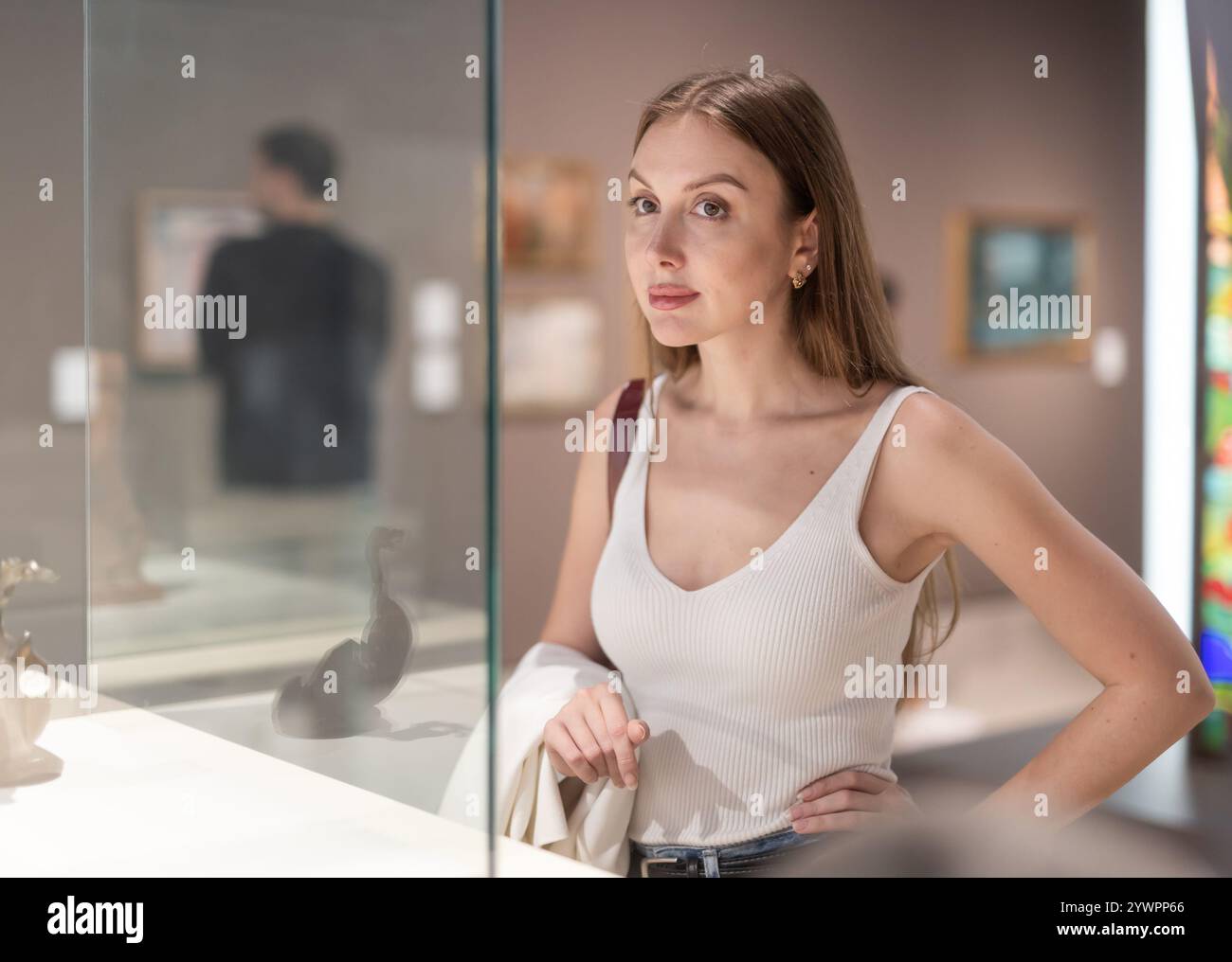 Young female visitor stands near glass display case and examines ...