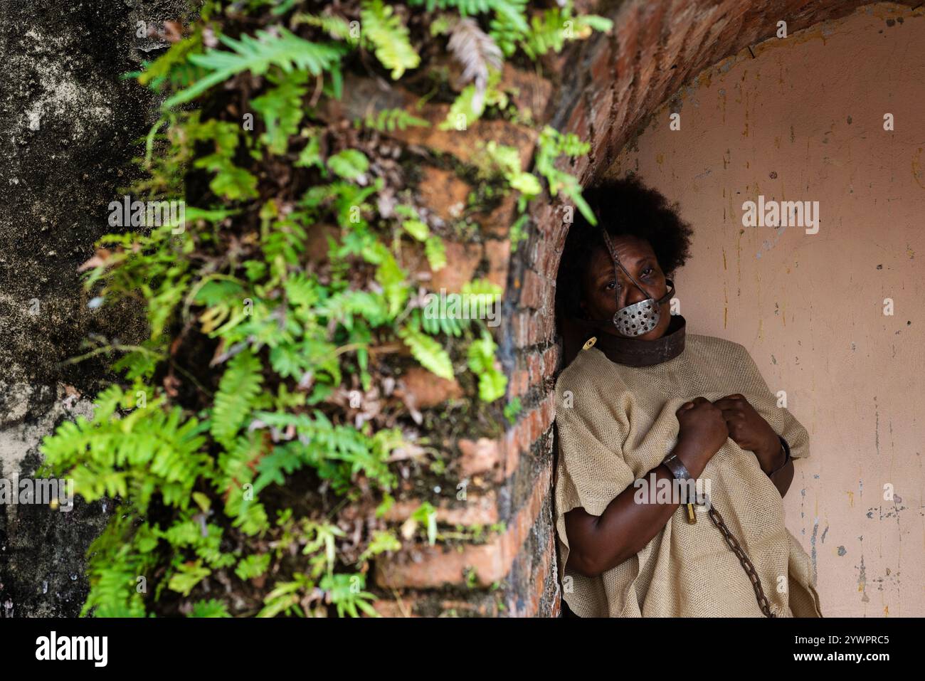 Black woman chained and with an iron mask on her face leaning against a ...