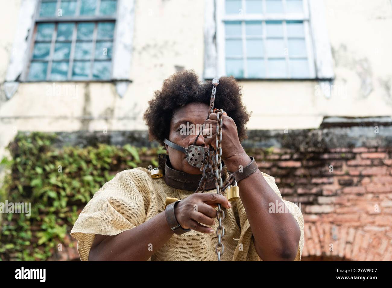 Black woman dressed as a slave, chained and with an iron mask on her ...