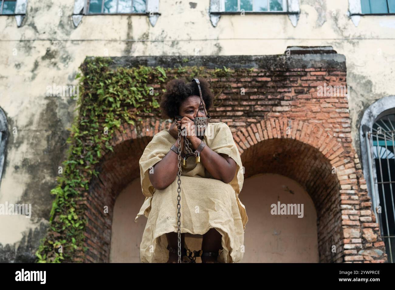 Black woman dressed as a slave, chained and with an iron mask on her ...