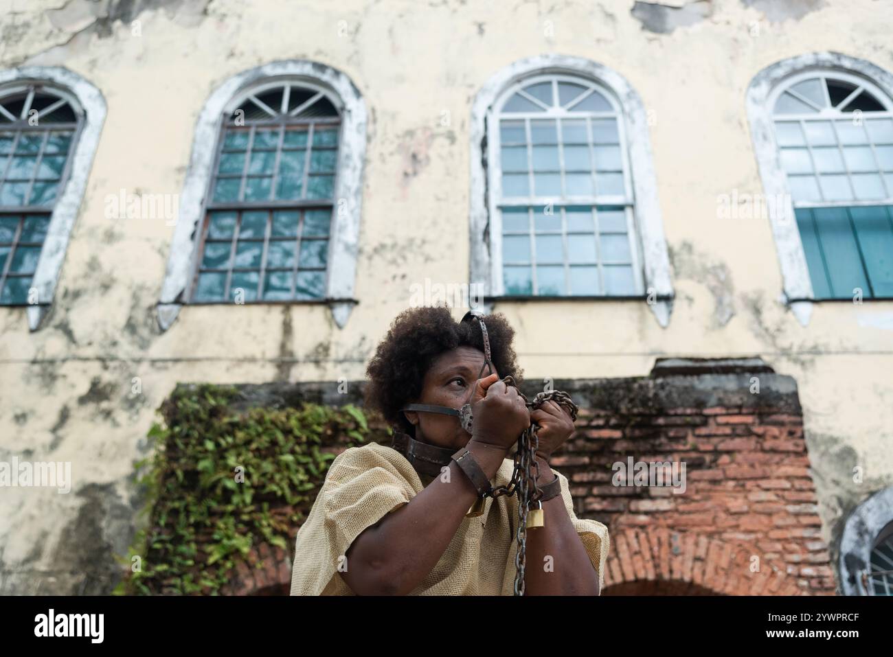Black woman dressed as a slave, chained and with an iron mask on her ...