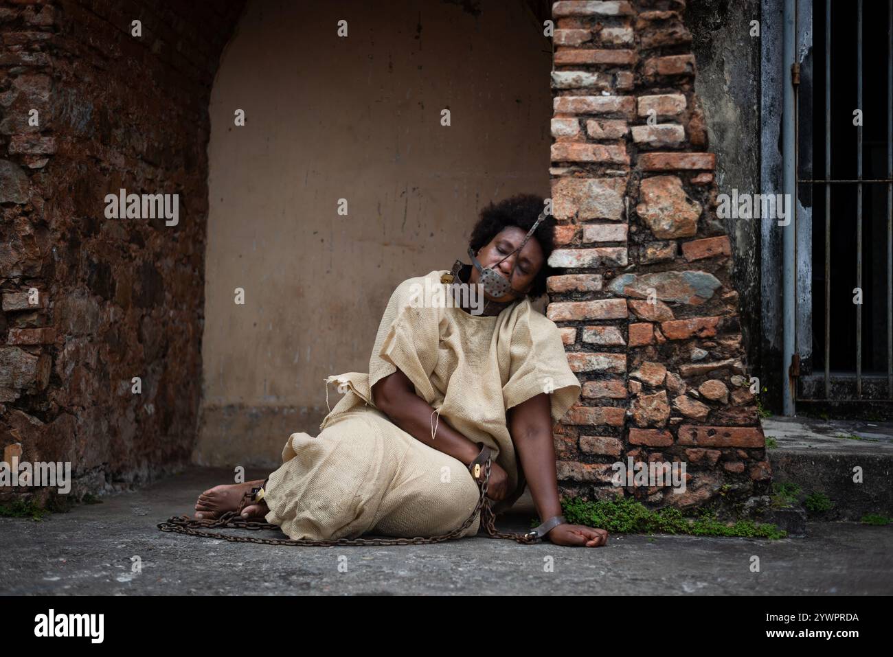 Black woman with an iron mask on her mouth and chained, sitting on the ...