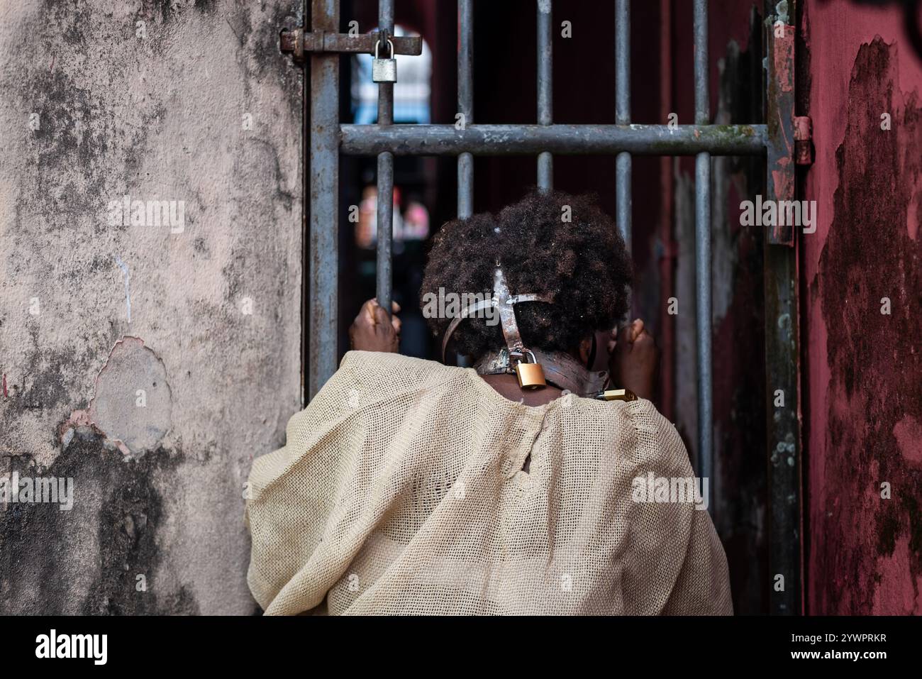 Portrait of a black woman dressed as a slave, chained with an iron mask ...