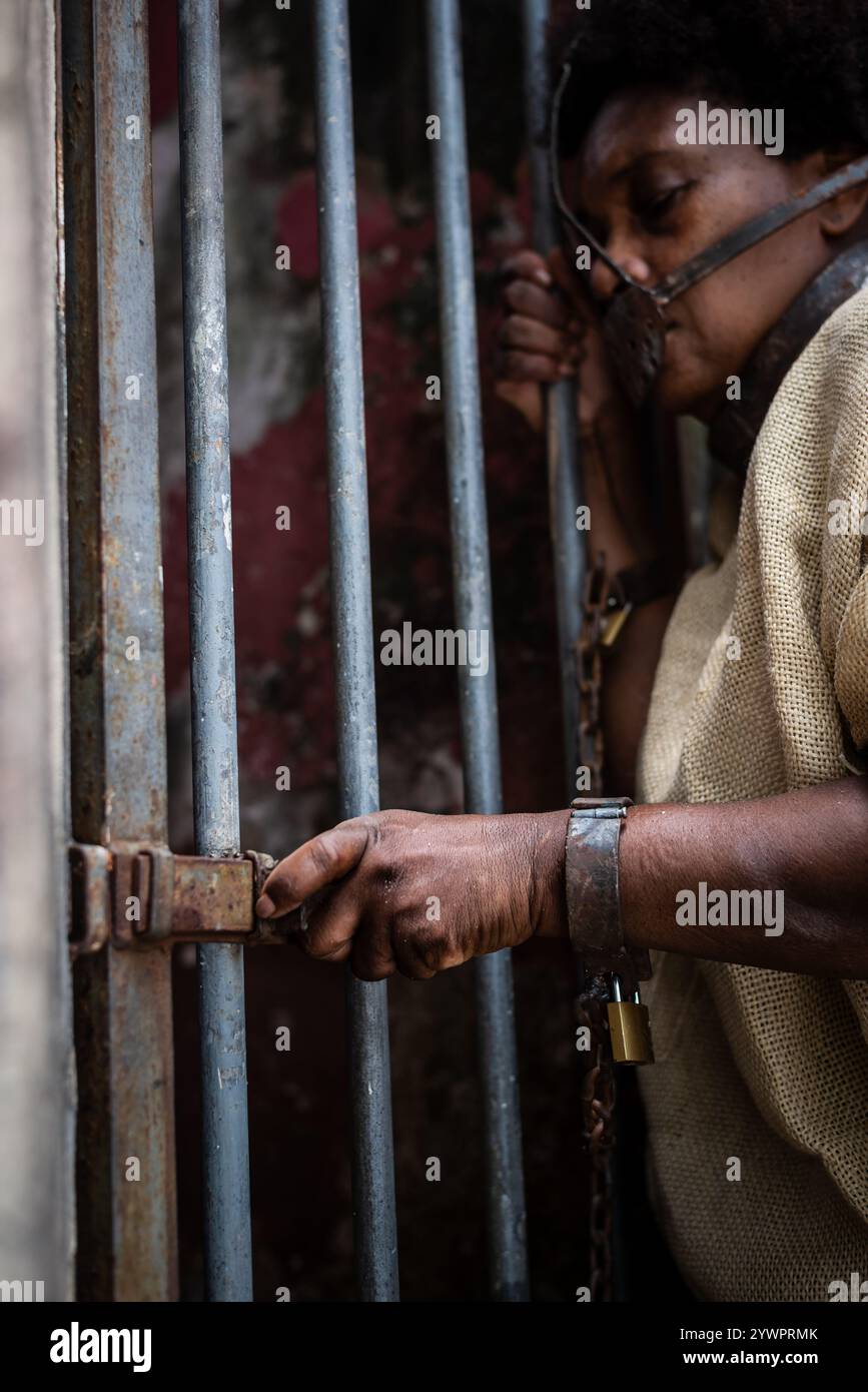 Black woman dressed as a slave, chained with an iron mask on her mouth ...