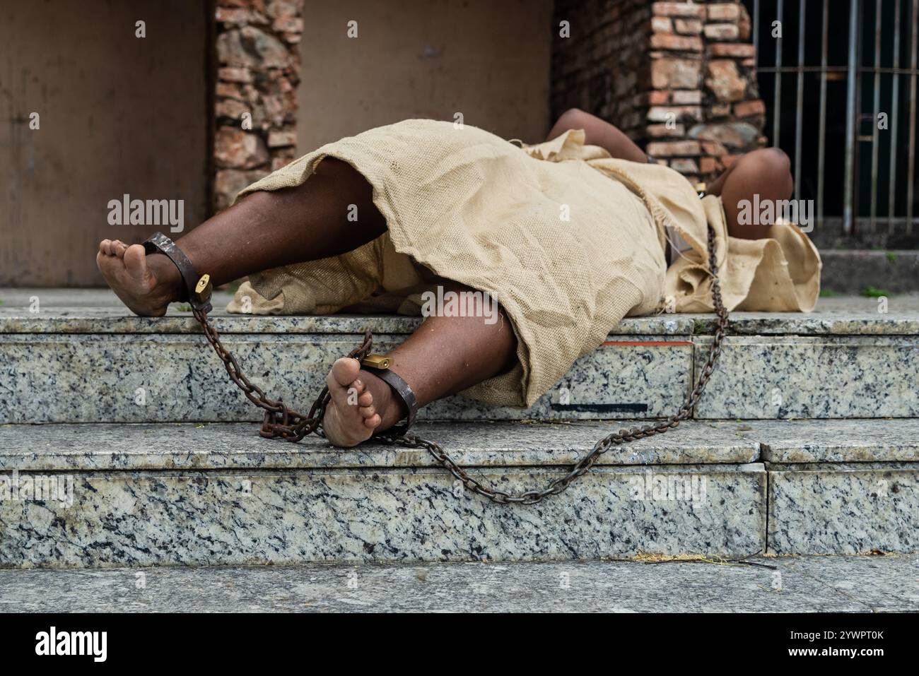 Black woman dressed as a slave in chains, lying on the stairs of a ...
