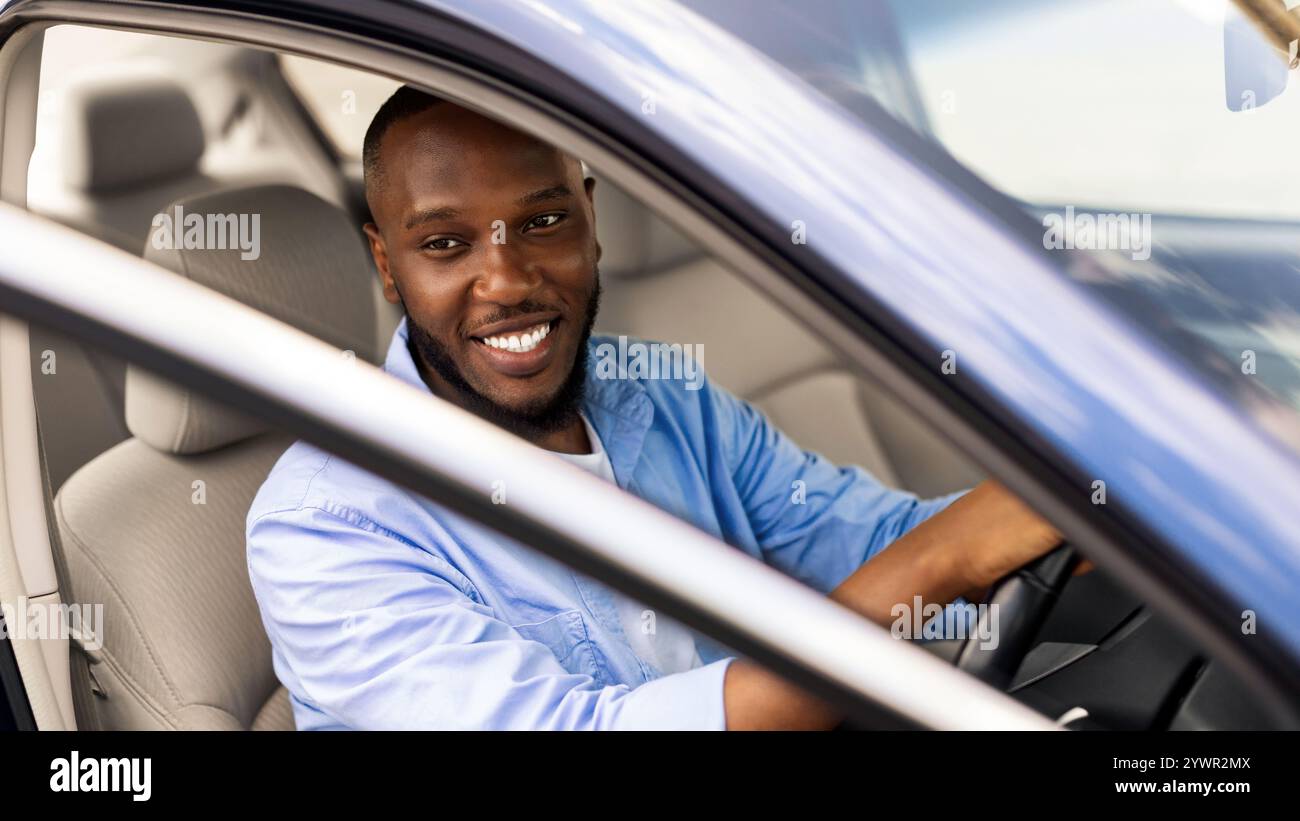 Smiling black man driving new car in the city Stock Photo - Alamy