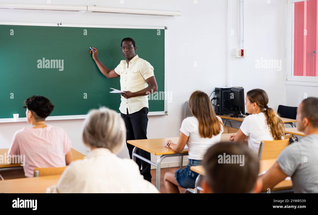 Male teacher explaining subject to students in classroom Stock Photo ...
