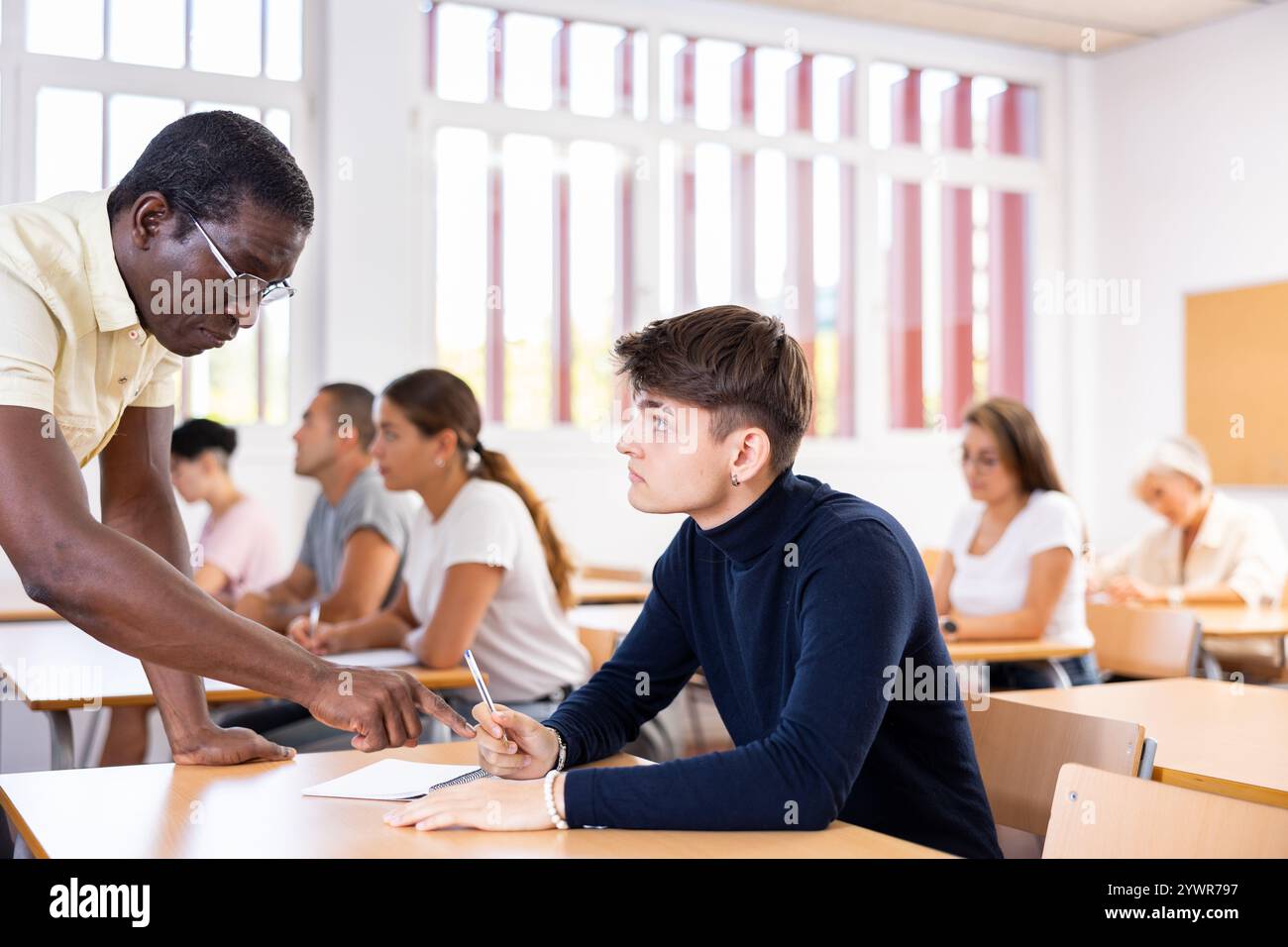 African American teacher helping student solve task during lesson Stock ...