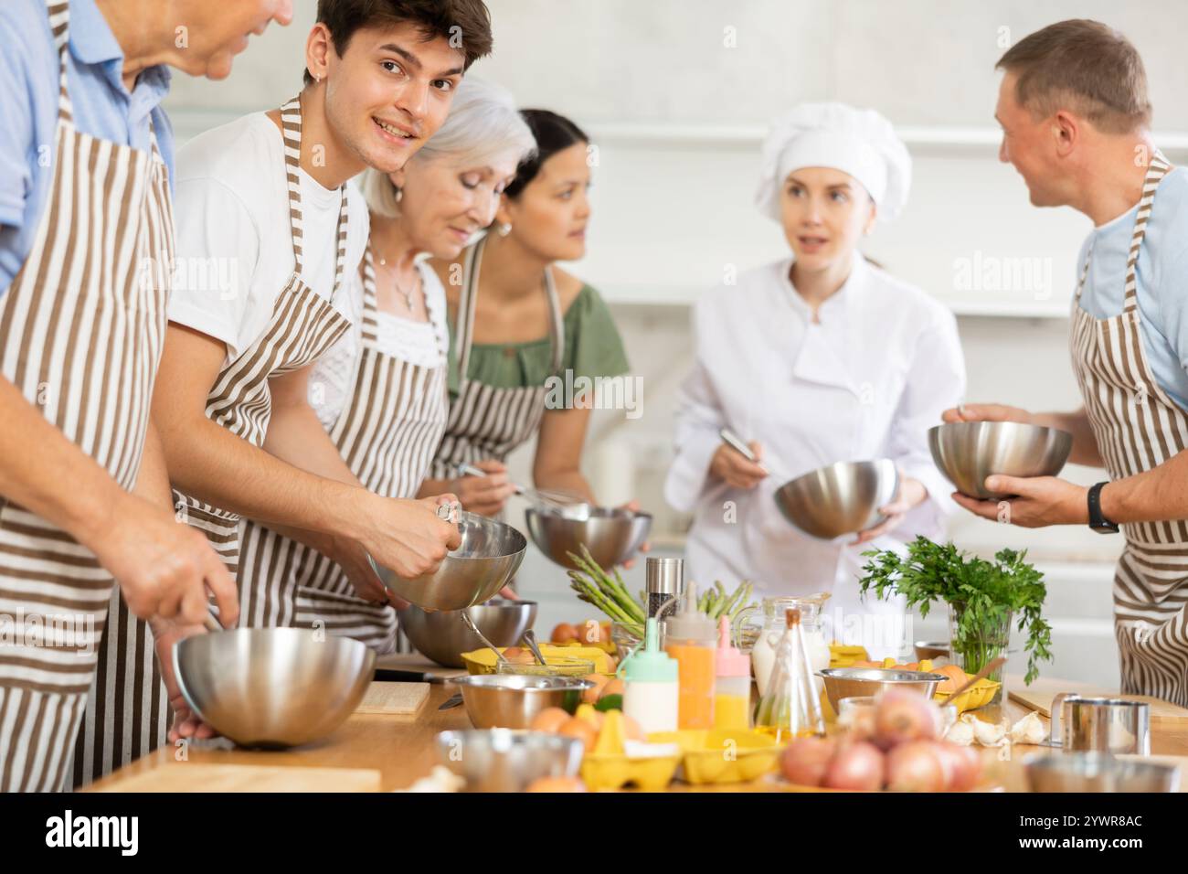 Female chef giving instructions to students standing around table in ...
