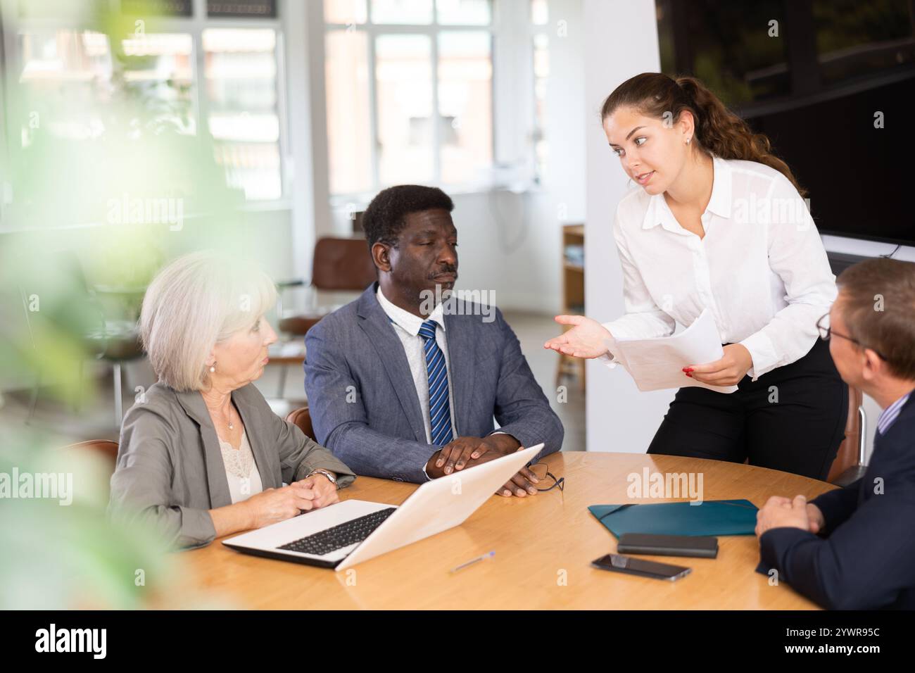 Positive business partners engaged in conversation sitting around table ...