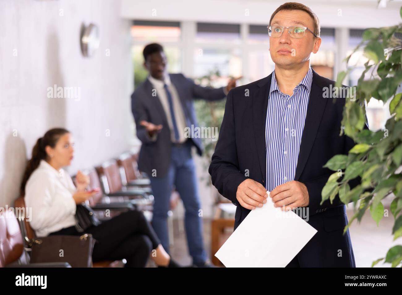 Upset middle-aged man standing in waiting room with his back to person ...