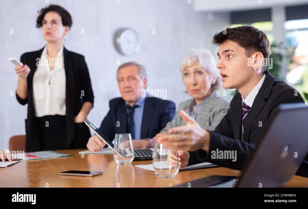 Young businessman asking questions during presentation of partners ...