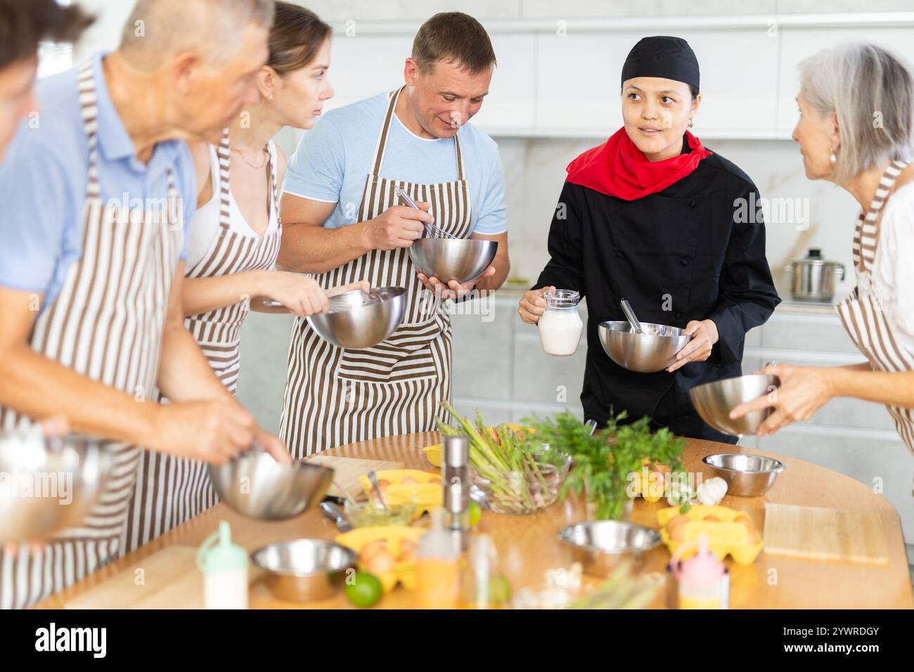 Young woman teaching group of people how to cook Stock Photo - Alamy