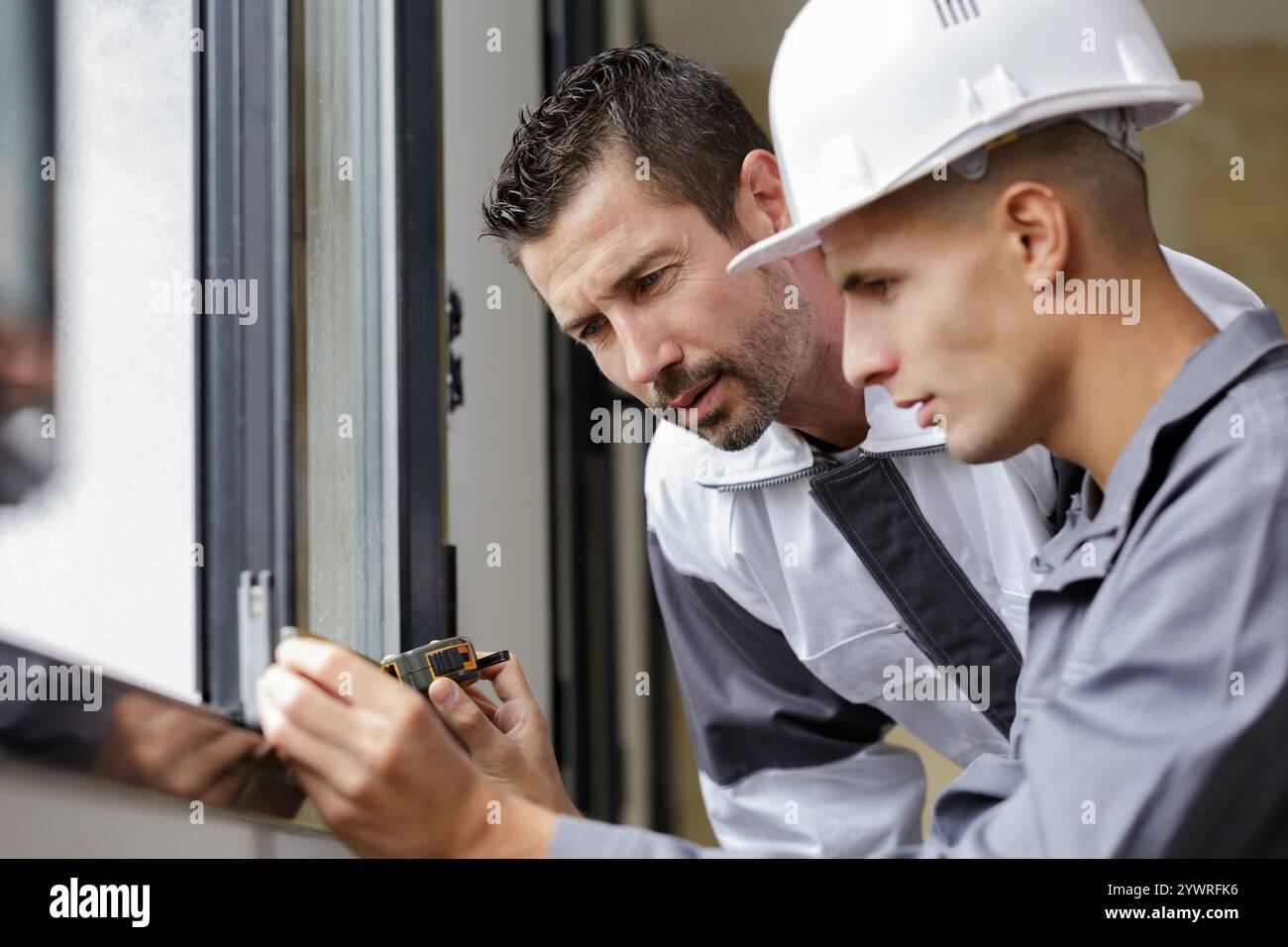 two men measuring a window Stock Photo - Alamy