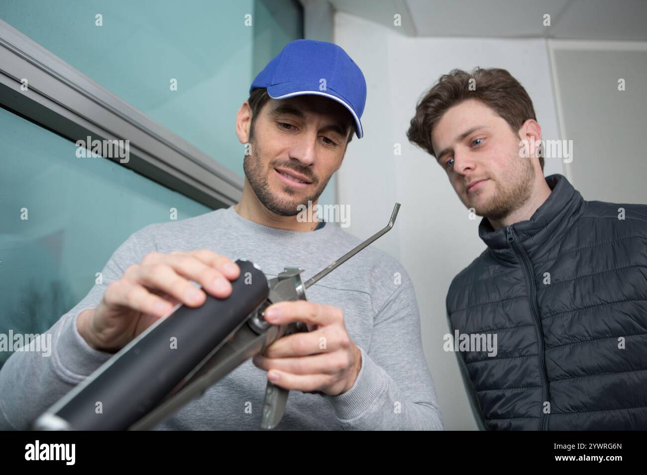 apprentice being shown how to insert caulk catridge Stock Photo - Alamy