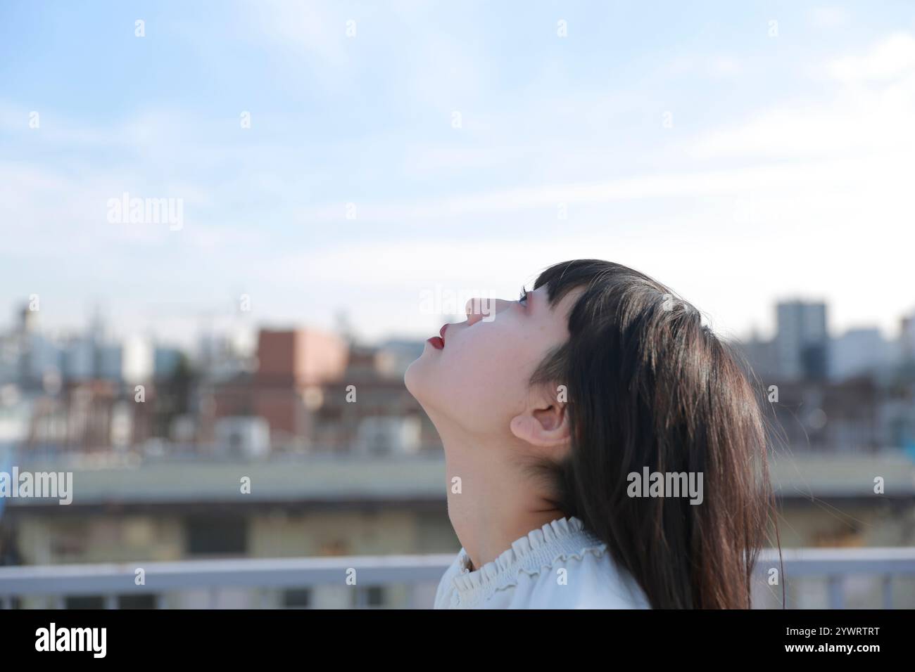 Side view of woman looking up at sky on rooftop Stock Photo - Alamy