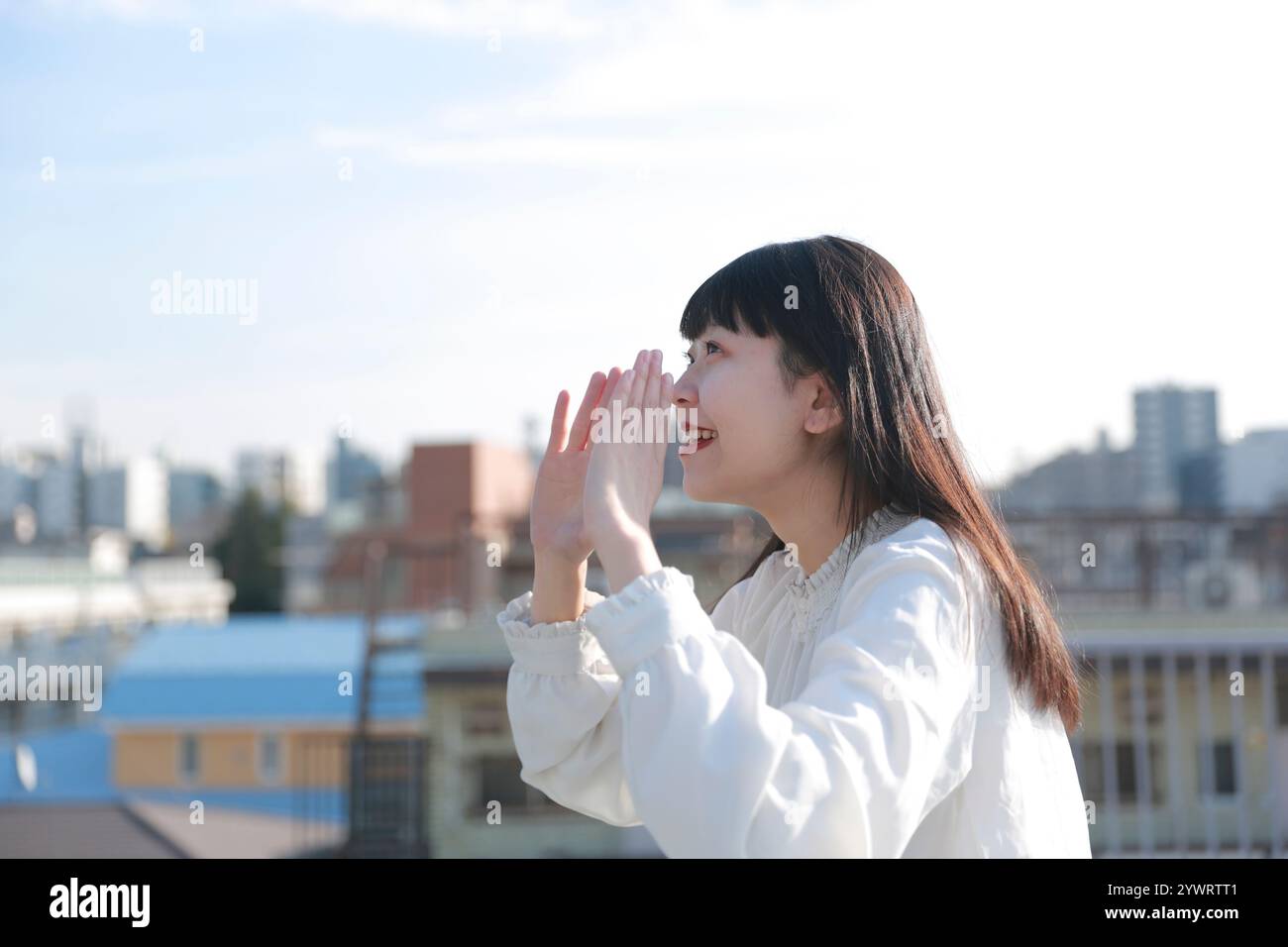 Woman on rooftop holding hands in front of mouth and shouting Stock ...