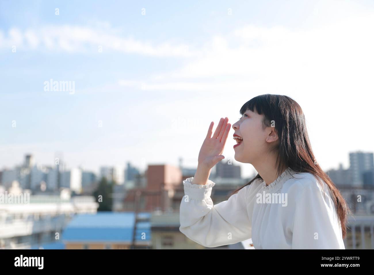 Woman shouting on rooftop with hand in front of mouth Stock Photo - Alamy