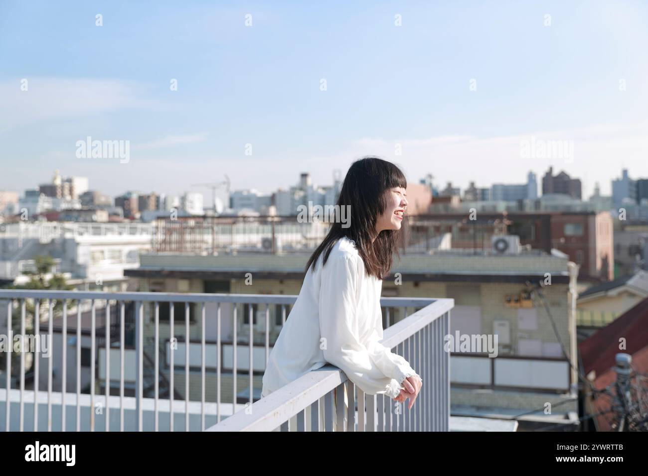 Smiling woman leaning over railing on rooftop Stock Photo - Alamy