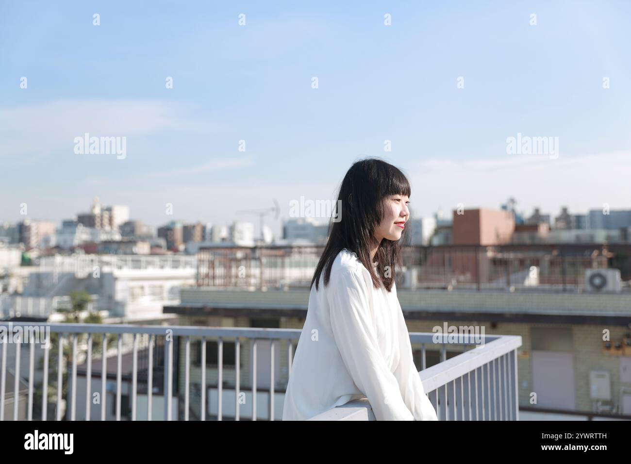Woman leaning over railing on rooftop Stock Photo - Alamy