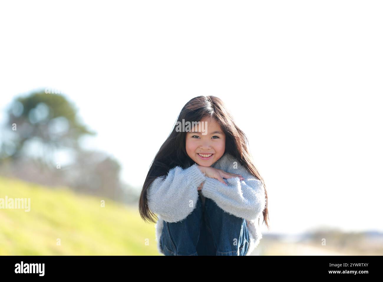 Smiling girl holding her knees and resting her chin on her overlapping ...