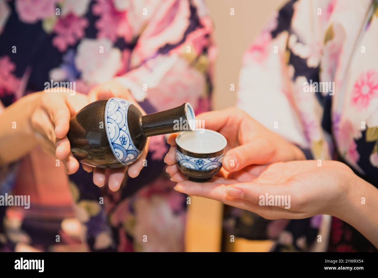Hands of two women in yukata pouring sake Stock Photo - Alamy